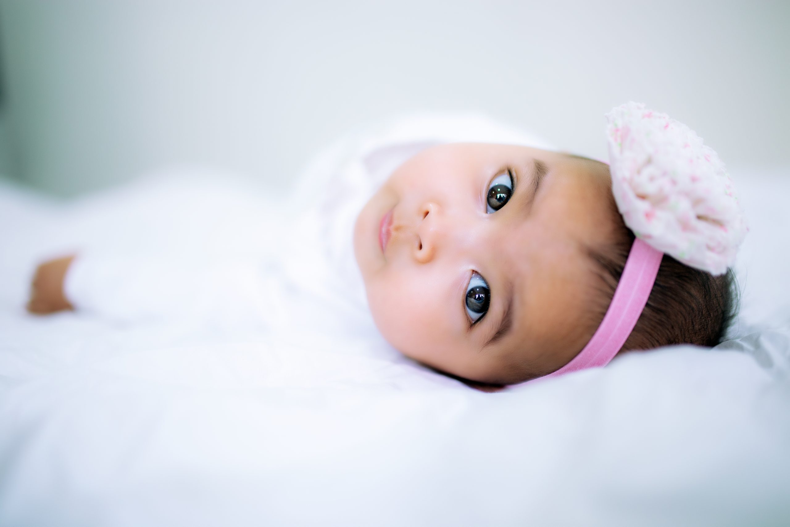 Portrait of a baby of 6 months lying on the white bed. | Ruah Woods ...
